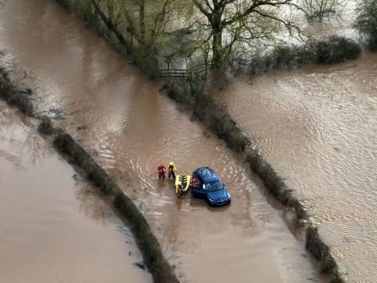 Dramatic photo shows woman being rescued after car gets stuck in flood ...