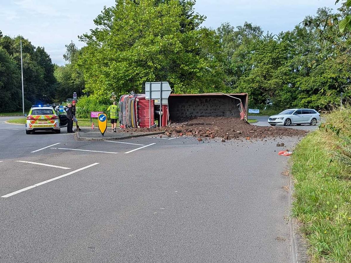 Driver injured as lorry crashes onto its side at roundabout spilling ...